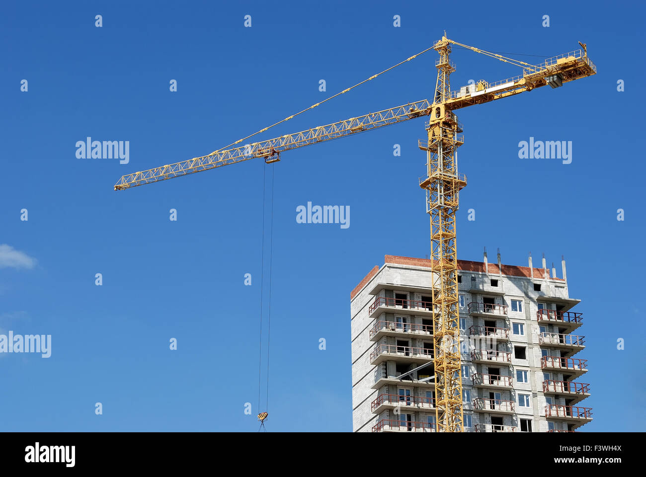Yellow tower crane at multistory building Stock Photo - Alamy
