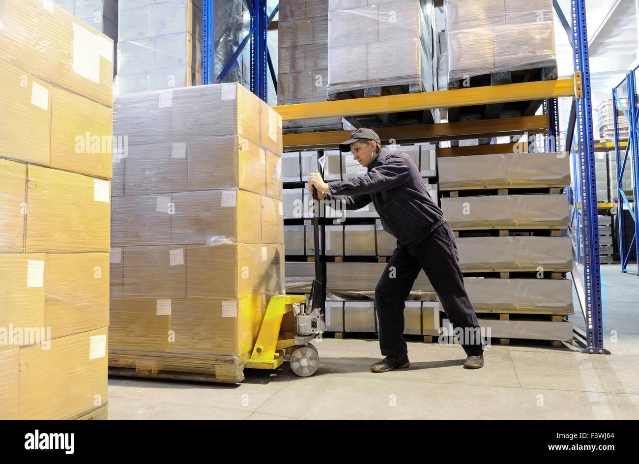 worker at warehouse with loader Stock Photo - Alamy