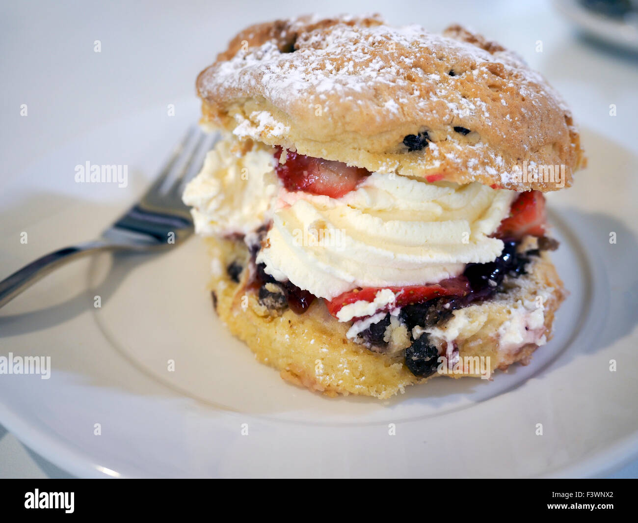 Cream scone served on plate with fork England Stock Photo - Alamy