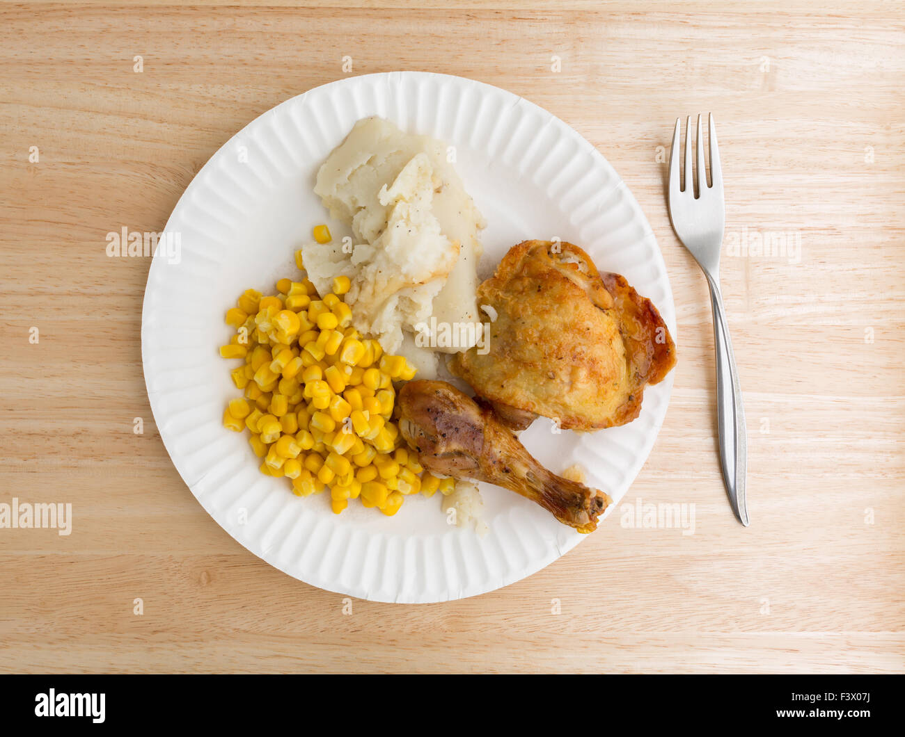 Top view of roasted chicken, mashed potatoes and corn on a white paper ...