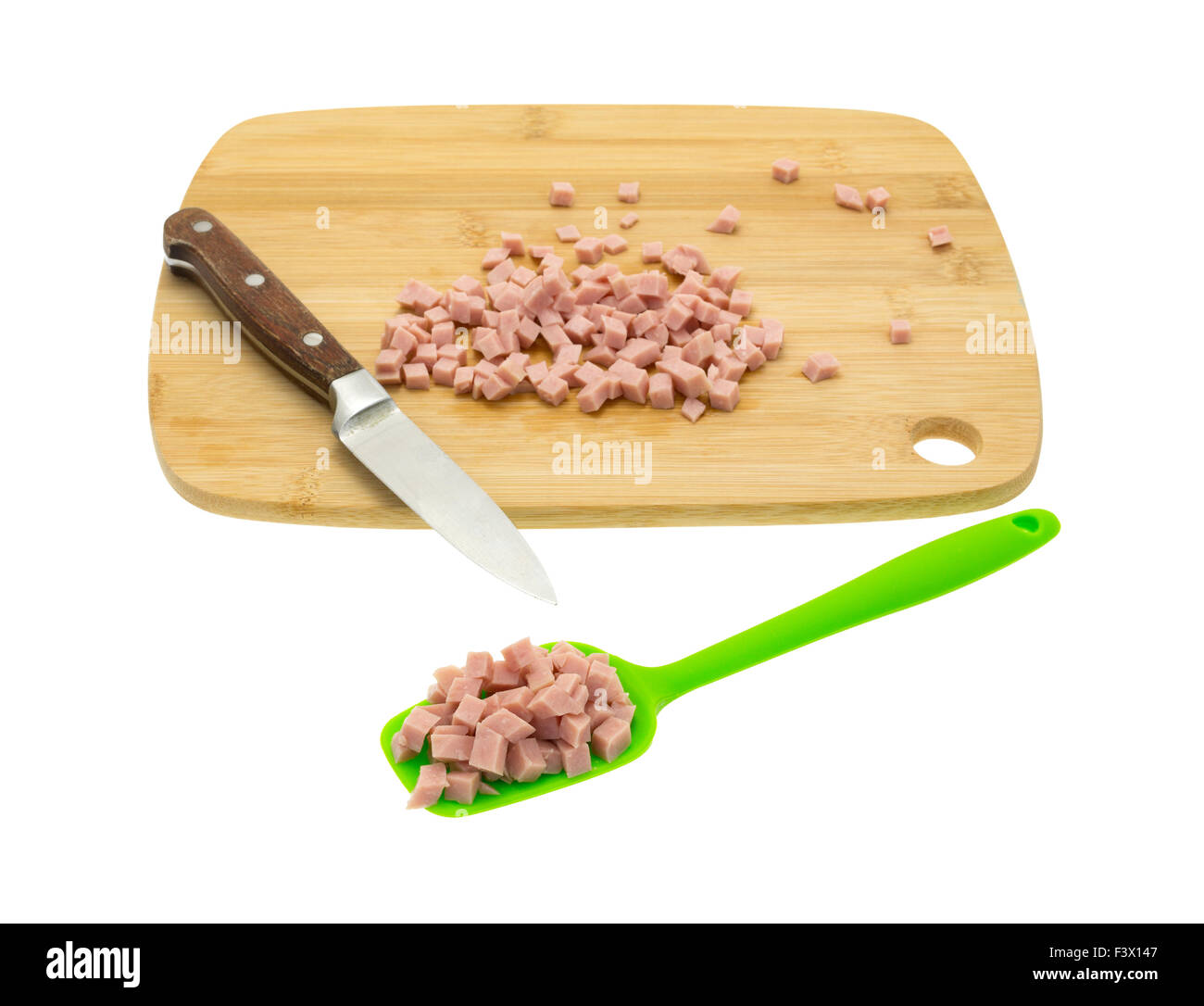 Diced ham on a cutting board with knife plus a green spoon isolated on ...