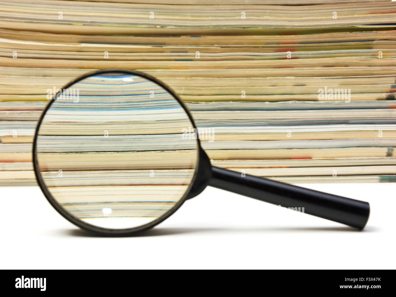 magnifying glass and stack of magazines Stock Photo - Alamy