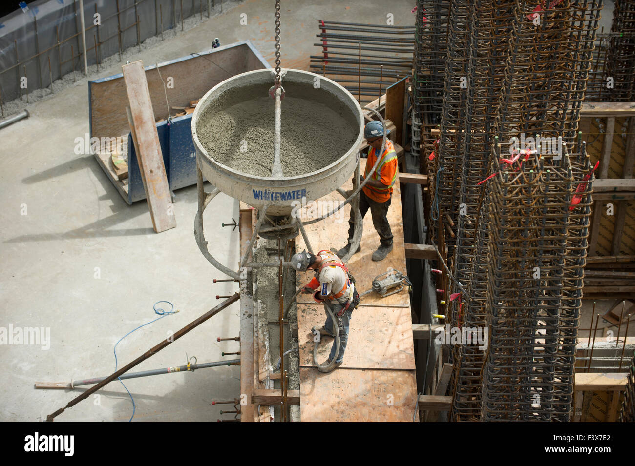 Construction workers pouring concrete into rebar reinforced forms from ...