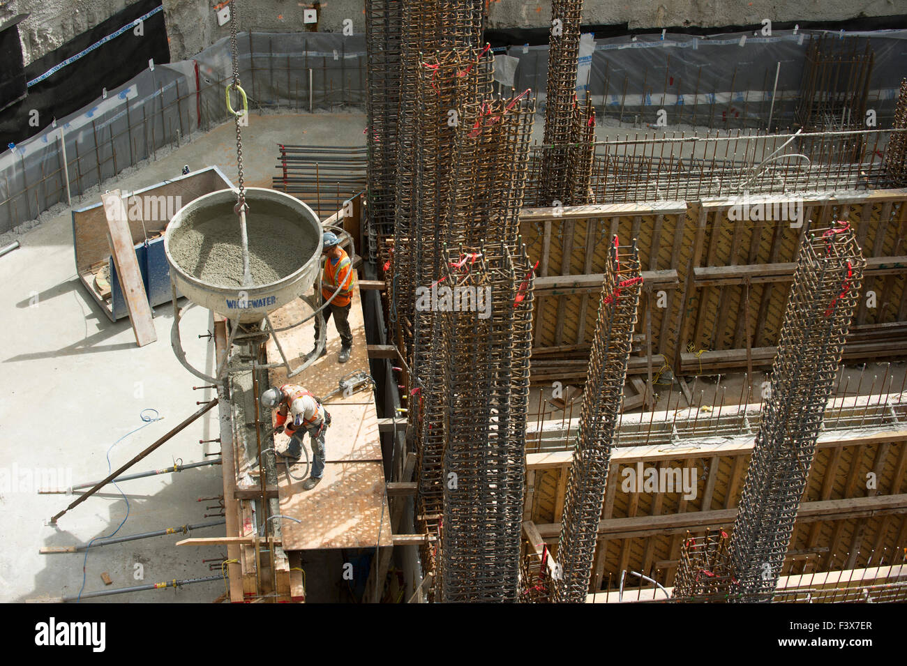 Construction workers pouring concrete into rebar reinforced forms from ...