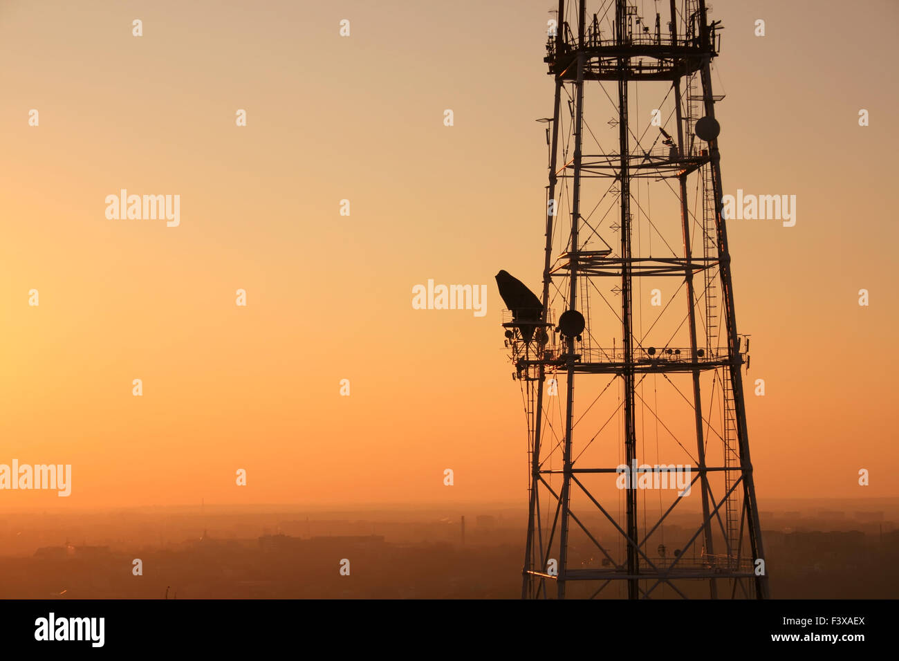Communication tower at sunset with cityscape Stock Photo - Alamy