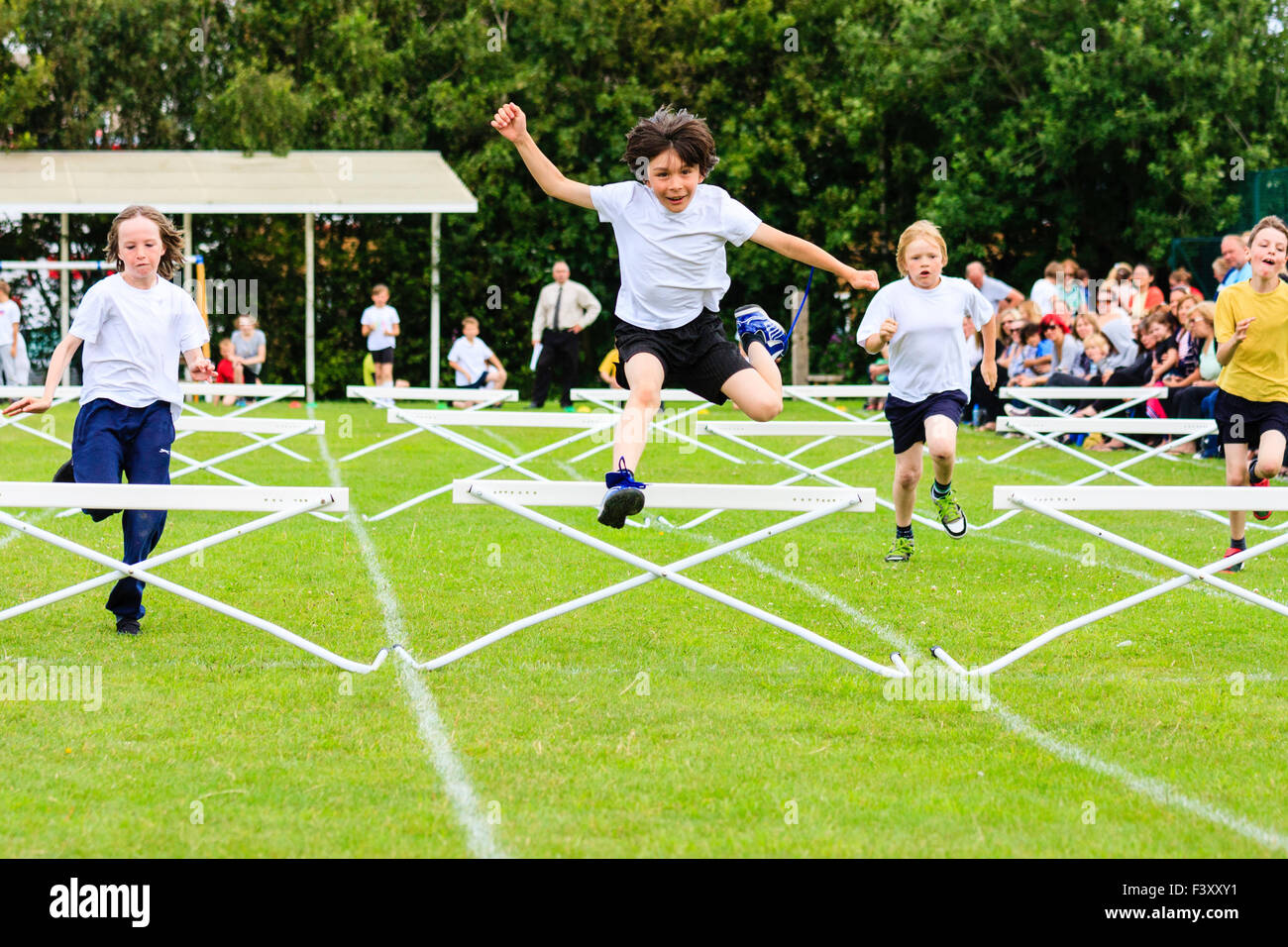 English school sports day. Children, boys, 10-11 year old, leaping over ...