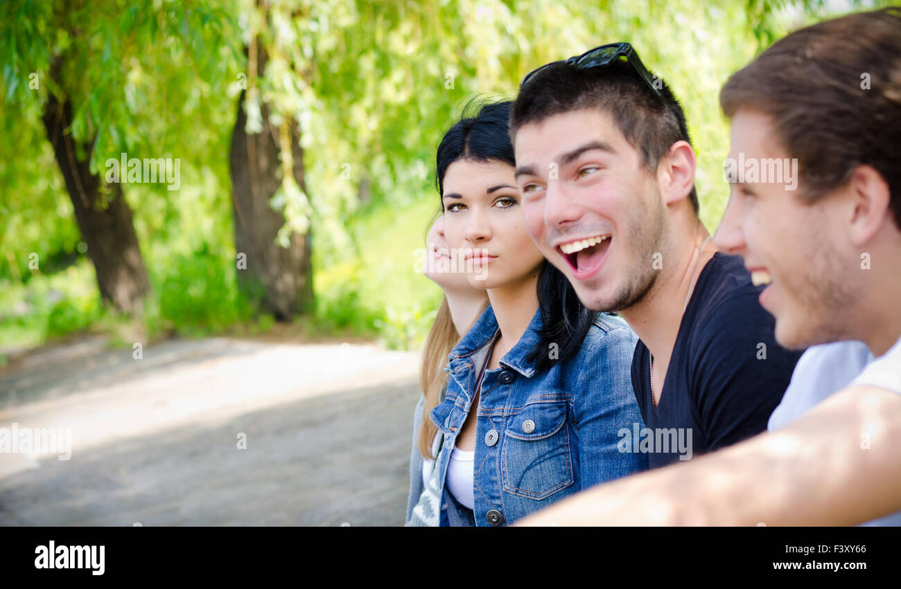 Row of friends sitting together on the park Stock Photo - Alamy