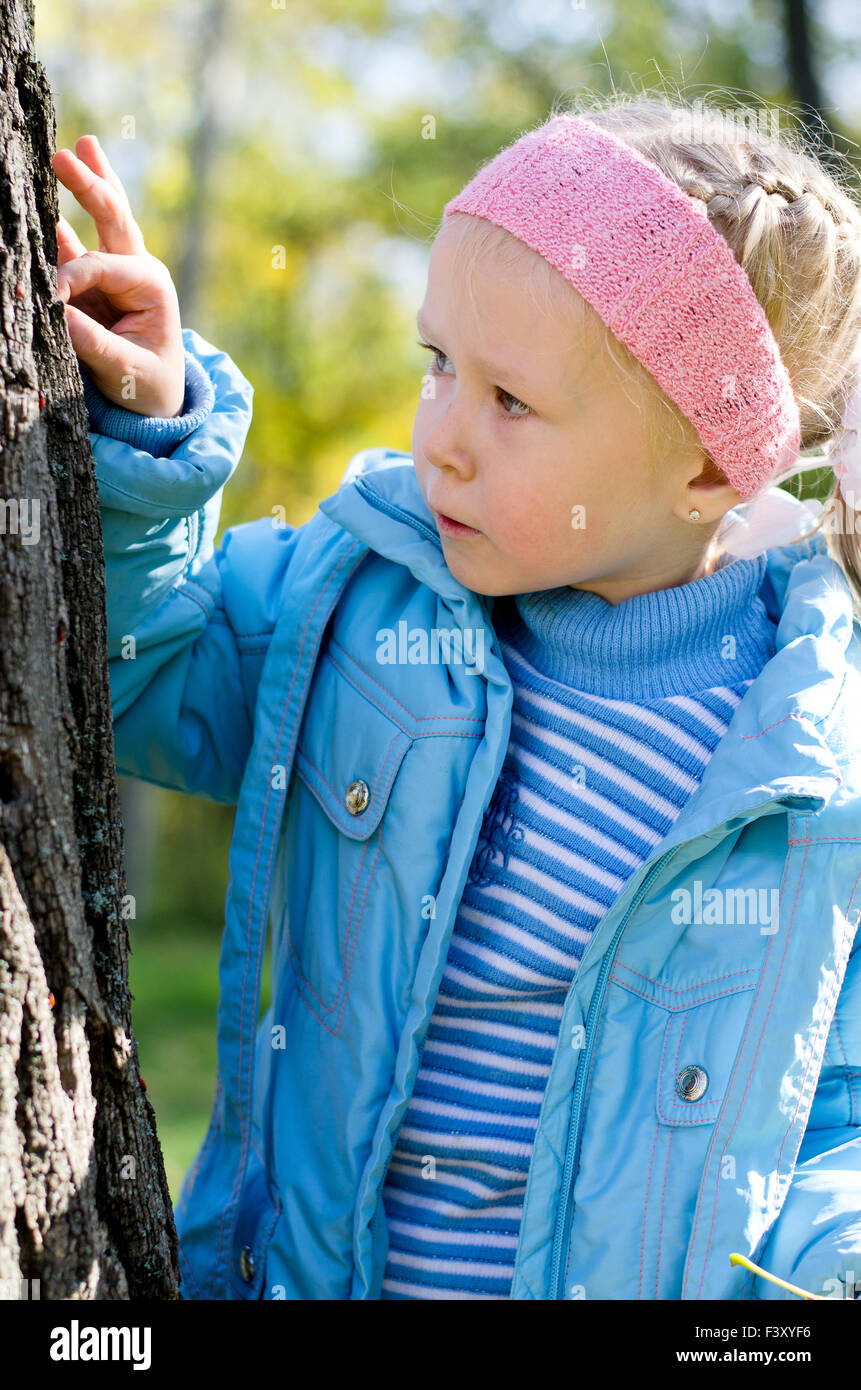 Little girl peering around a tree Stock Photo - Alamy