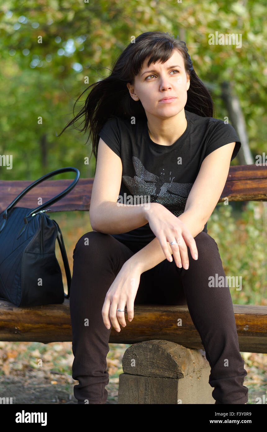 Woman sitting waiting on a country bench Stock Photo - Alamy