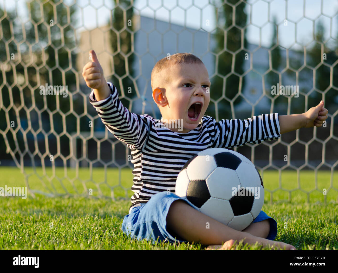 Boy with football shouting with glee Stock Photo - Alamy
