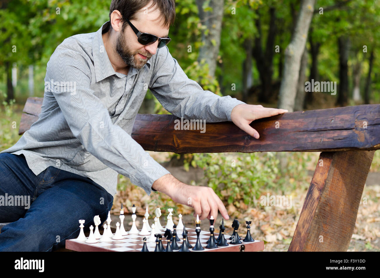 Man playing chess on a wooden bench Stock Photo - Alamy
