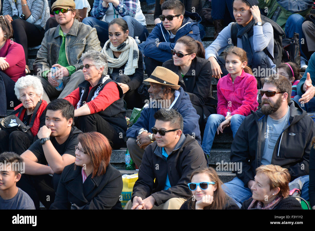 Multitude of diverse people in the USA sitting on bleachers reacting ...