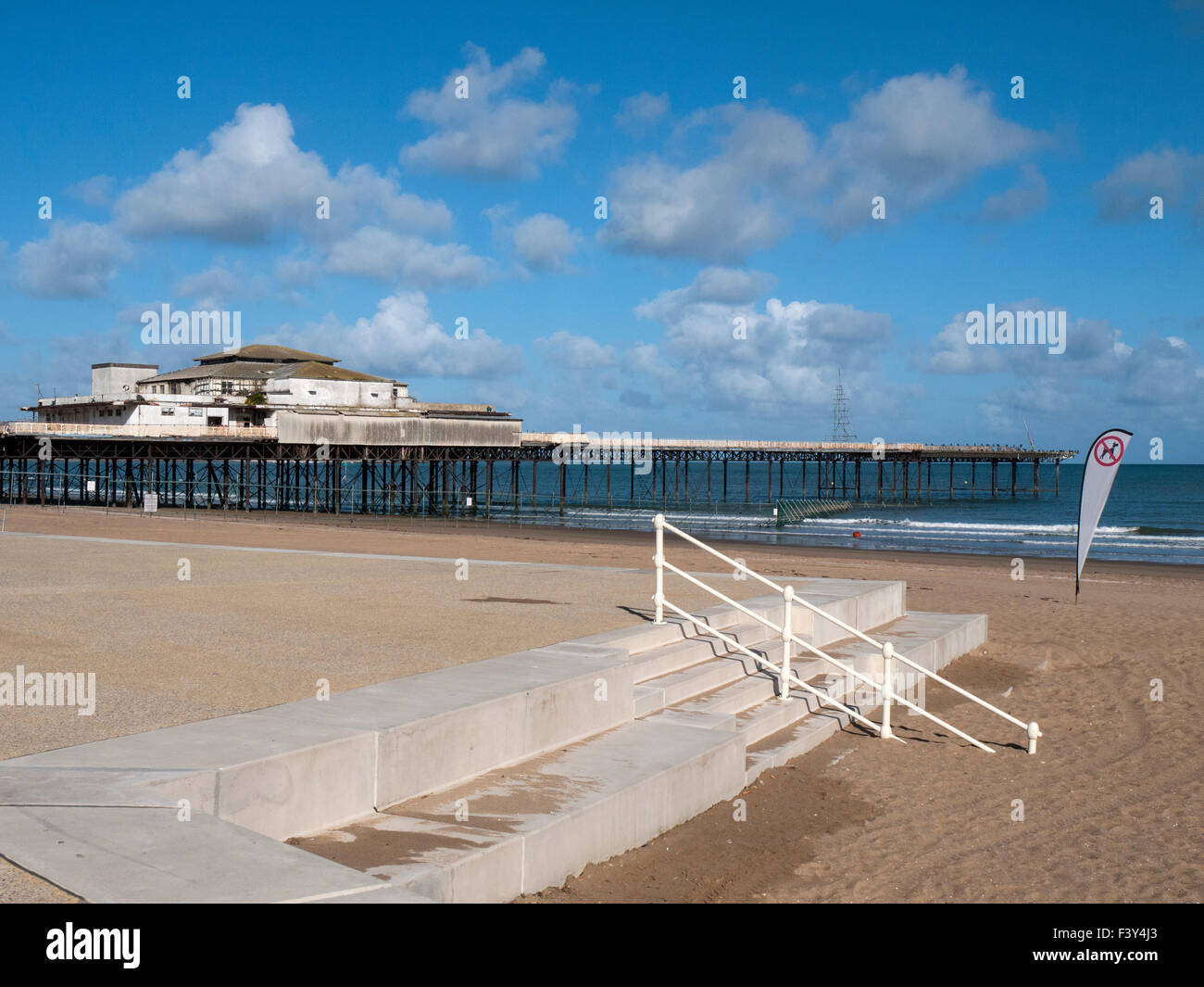 Derelict Victorian pier with no dogs allowed flag on sandy beach in ...