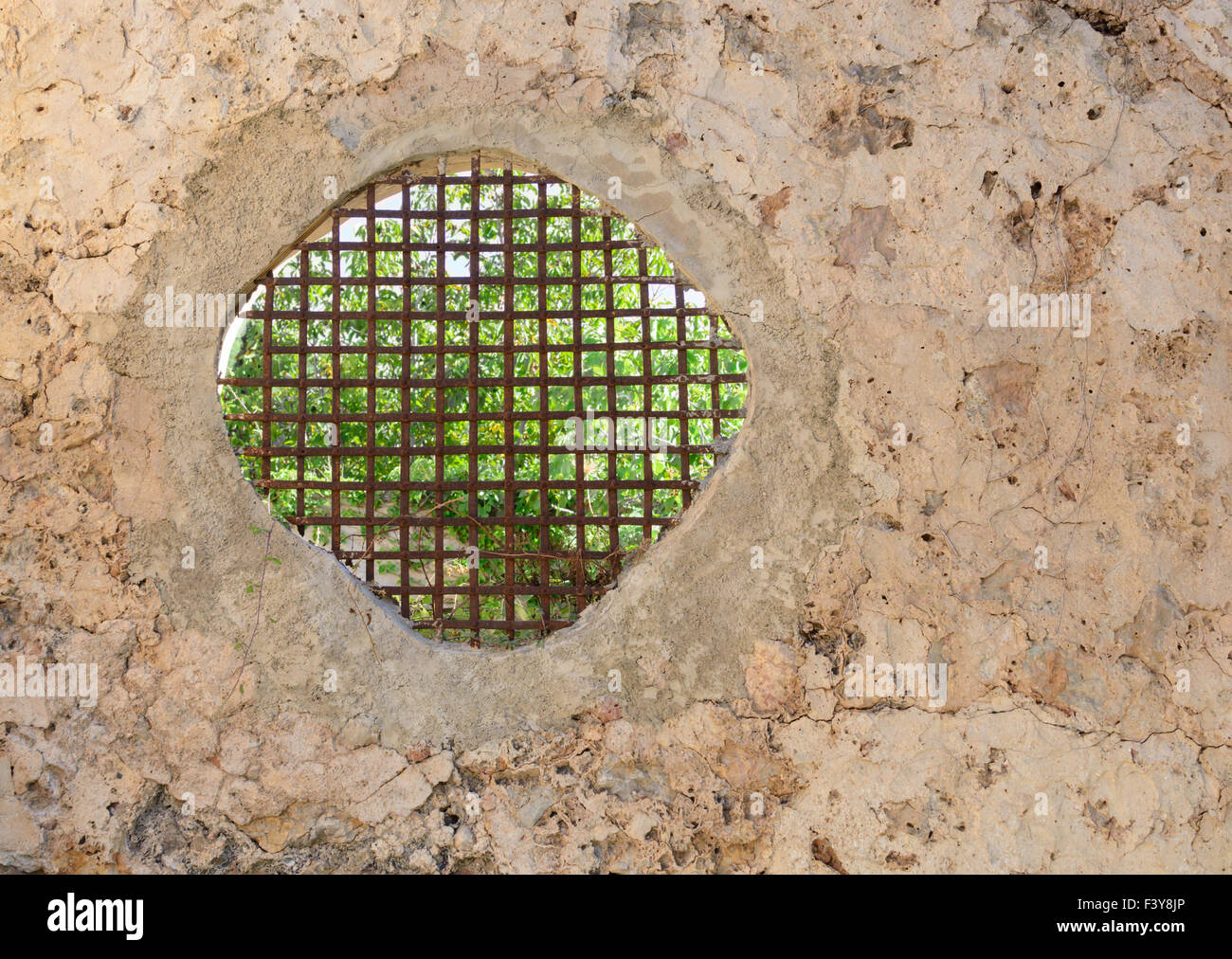 Opening with grid in old stone wall Stock Photo - Alamy