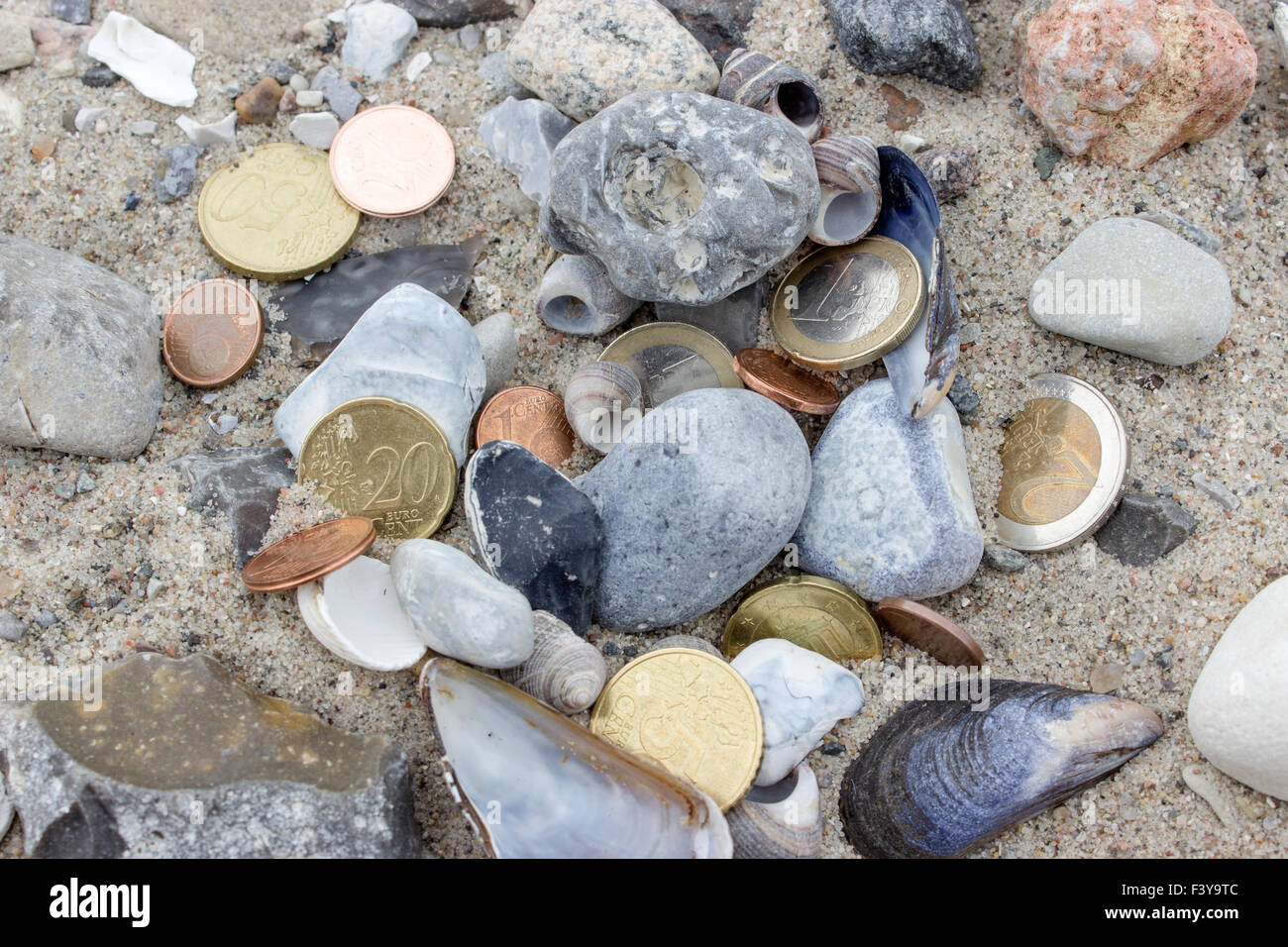 Coins, stones and shells in the sand Stock Photo - Alamy