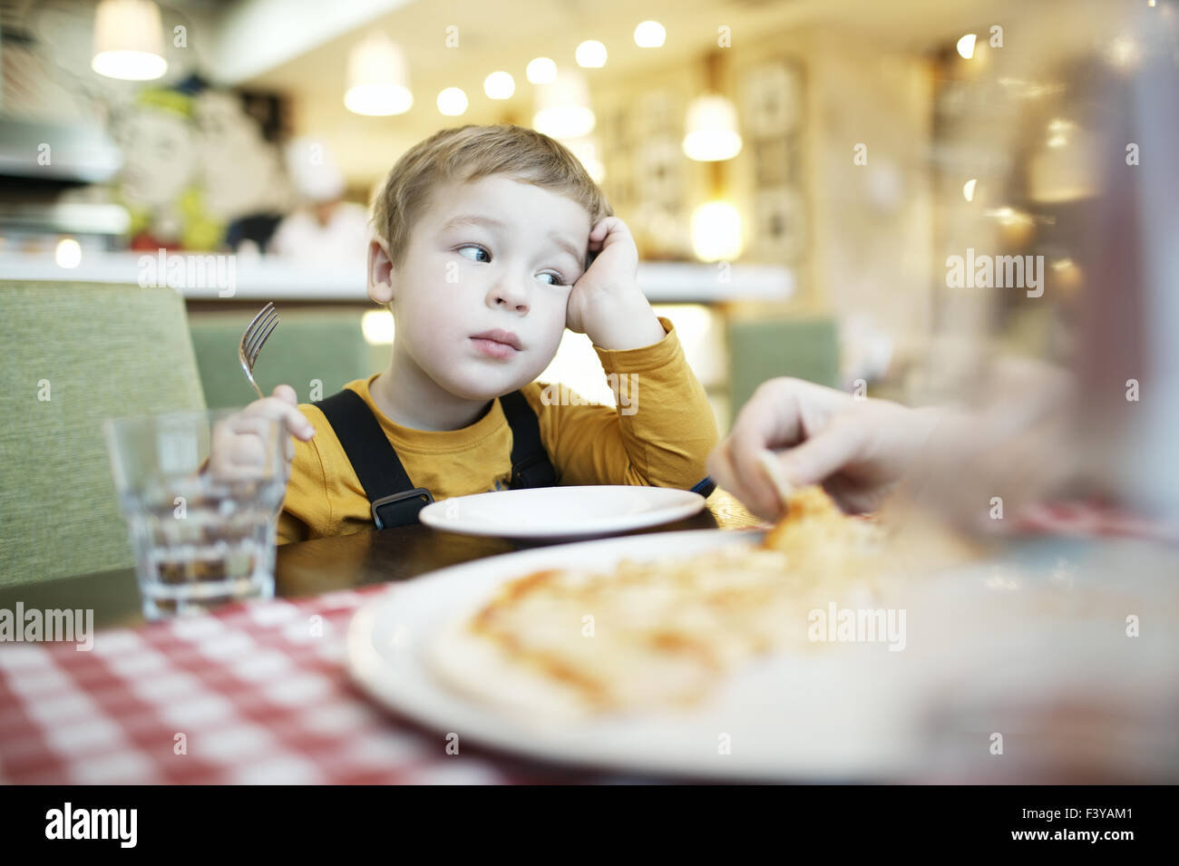 Bored little boy in a restaurant Stock Photo - Alamy