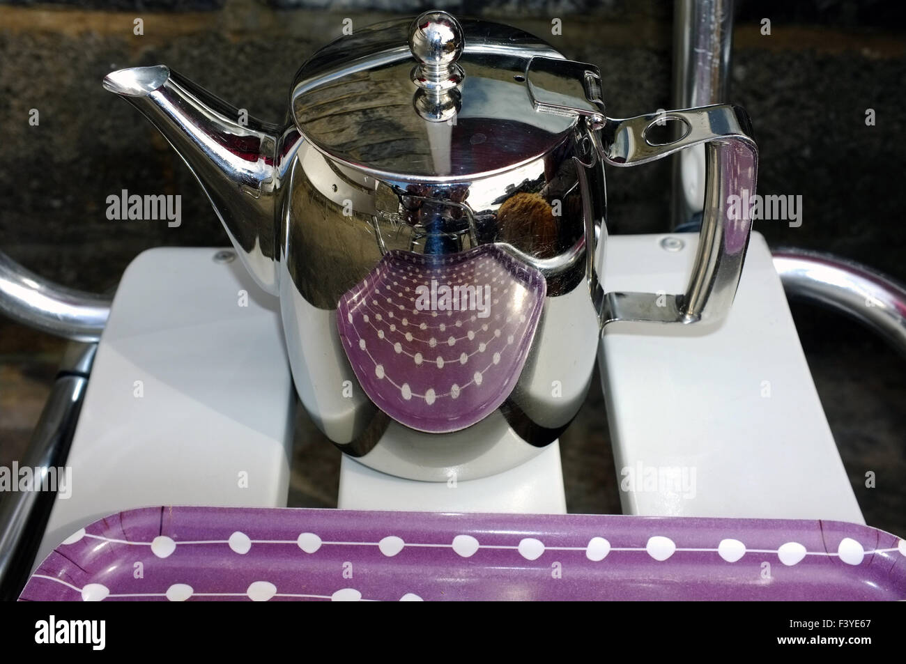 A purple tea tray reflected in a shiny metal teapot at a Welsh seaside ...