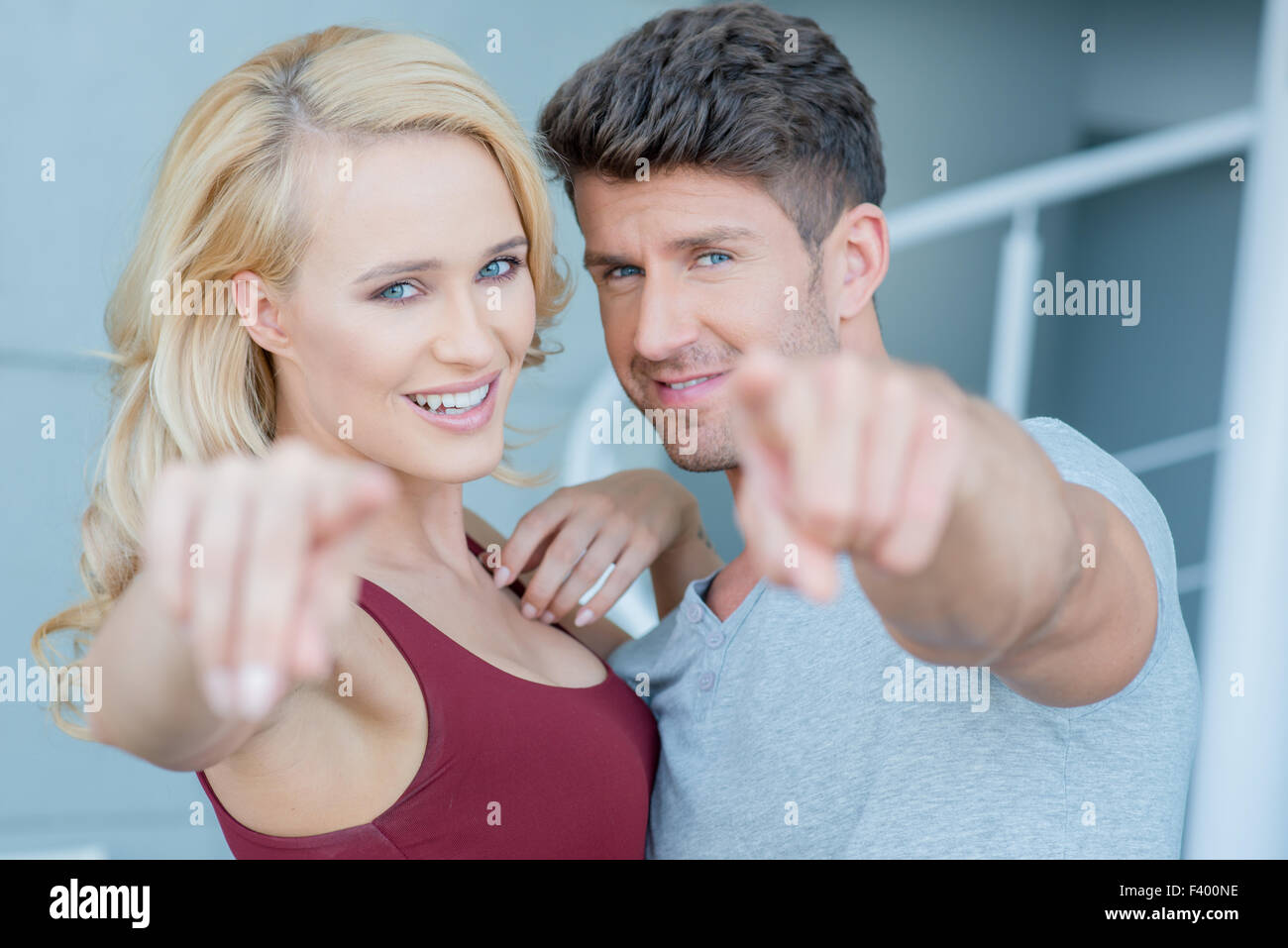 Smiling attractive couple pointing at the camera Stock Photo - Alamy