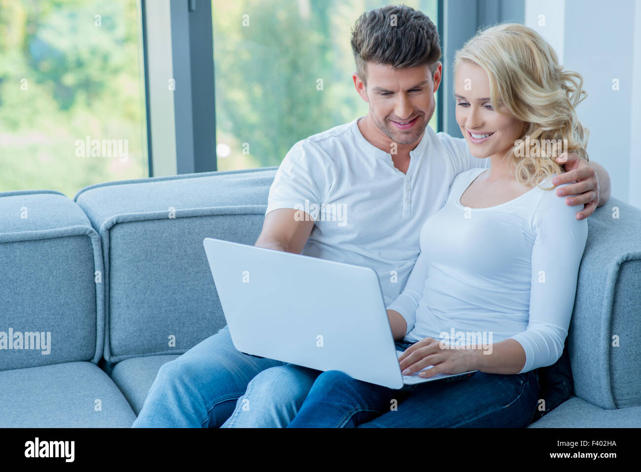 Young couple sitting sharing a laptop computer Stock Photo - Alamy