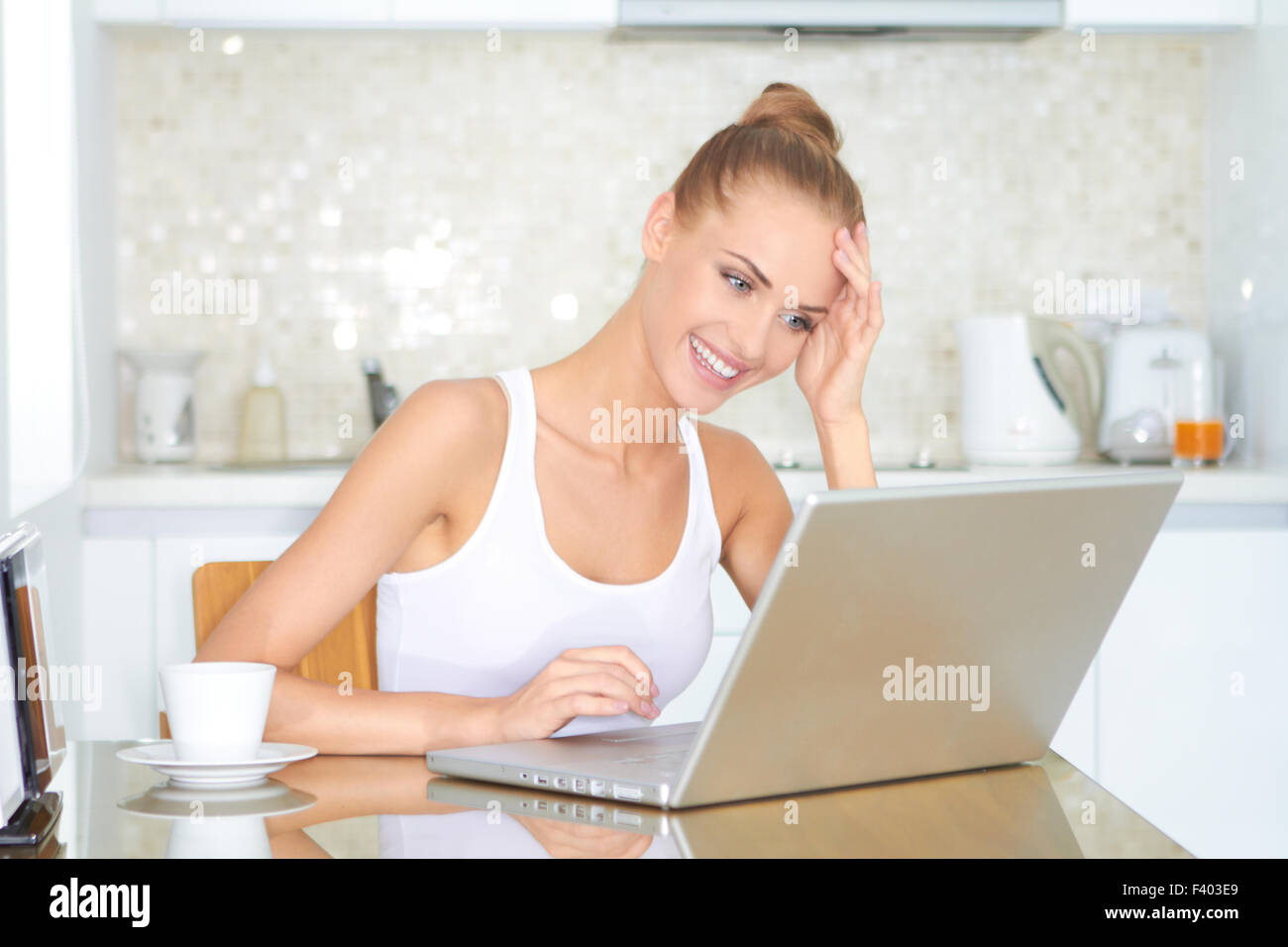Young woman working on a laptop in the kitchen Stock Photo - Alamy
