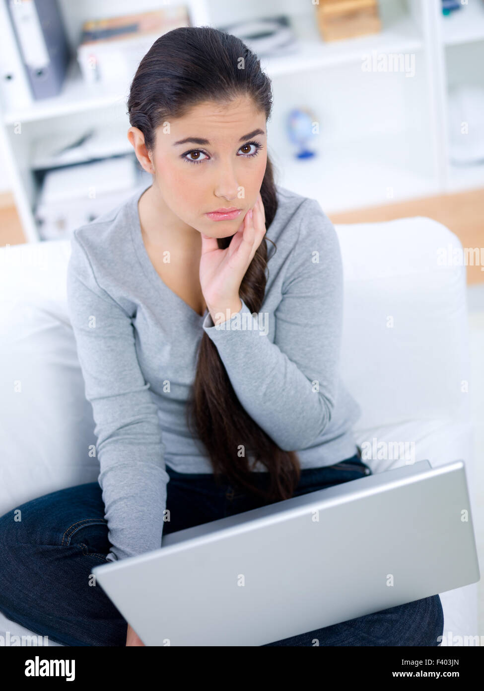 Lady sitting on sofa with concerned look Stock Photo - Alamy