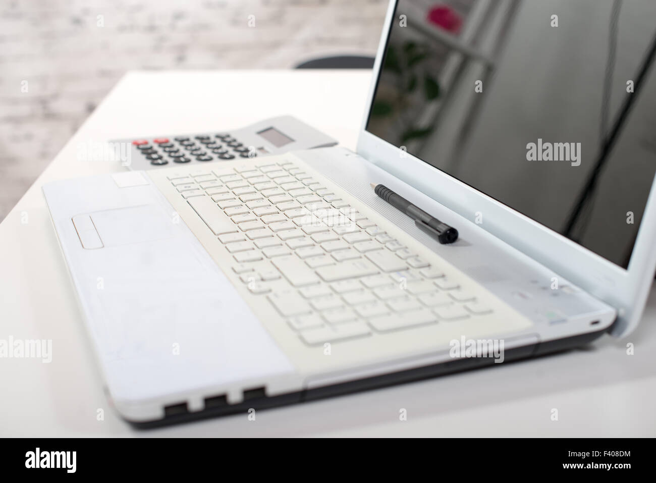 a computer, a calculator and a pen on a desk Stock Photo - Alamy
