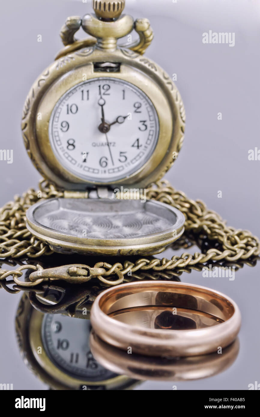 Pocket watch and a gold wedding ring Stock Photo - Alamy