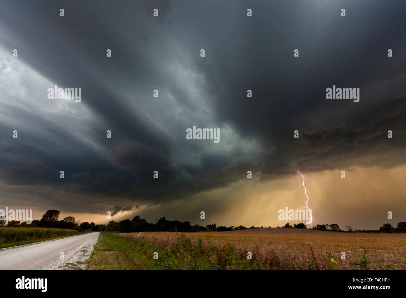 An outflow boundary moves over a field around sunset, as lightning ...