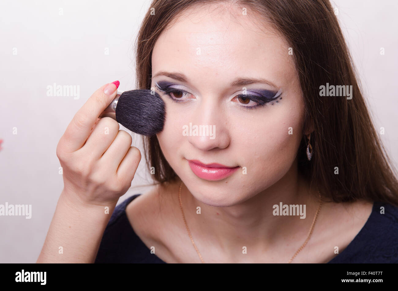 Beautiful young girl applying makeup on face Stock Photo - Alamy