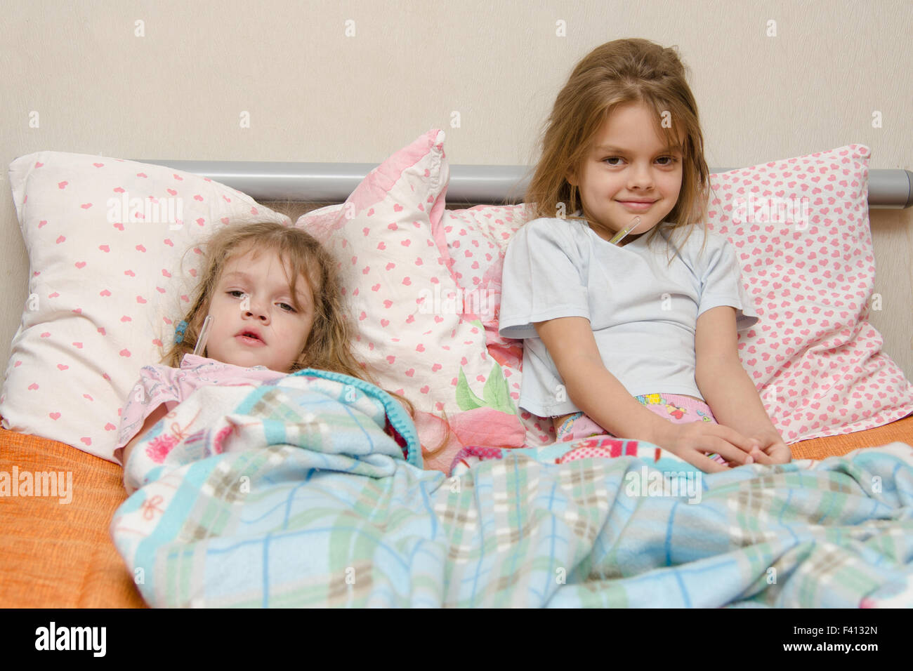 Two girls sick in bed with a thermometer Stock Photo - Alamy