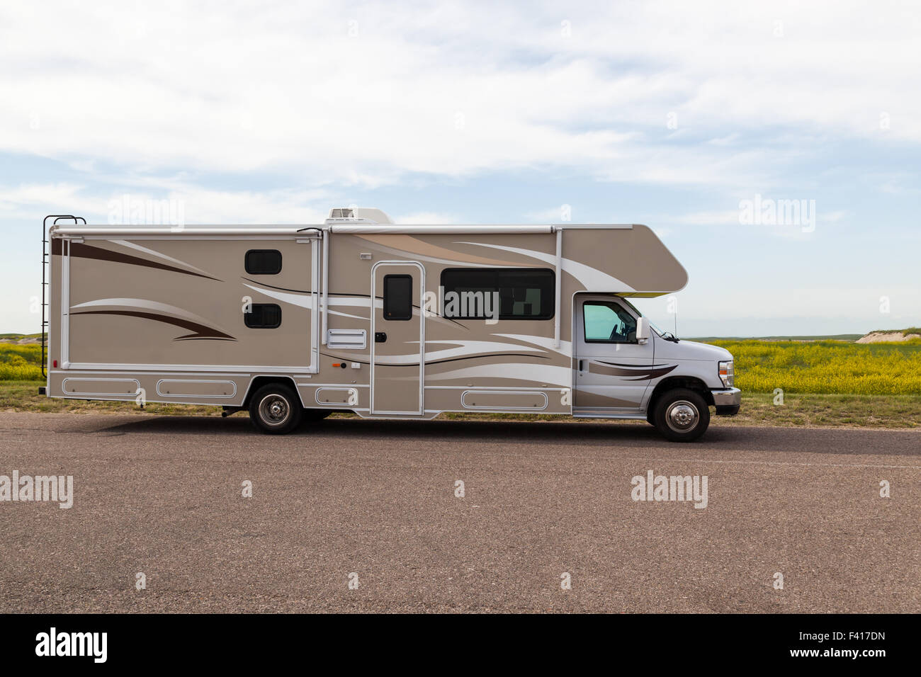 A brown and white motorhome parked on a plateau with a wildflower field ...