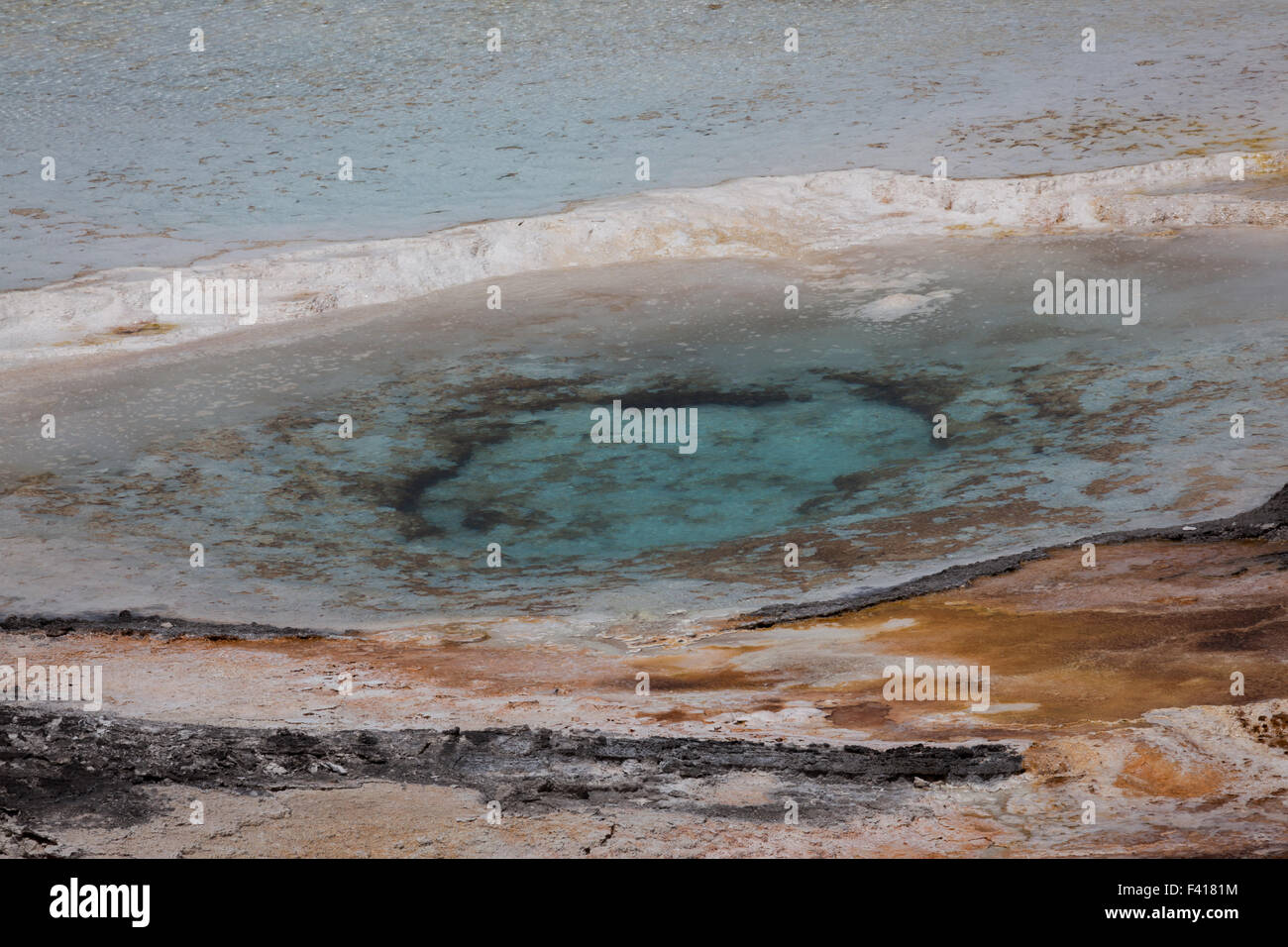 A volcanic pool of hot aqua blue water and rust colored surroundings at ...