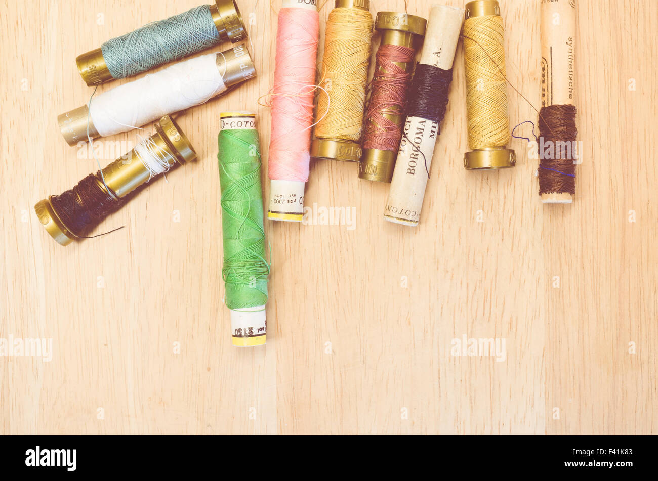 old sewing thread spools on natural wood background Stock Photo - Alamy