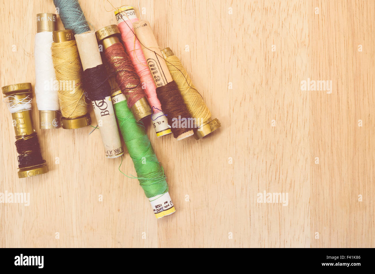 old sewing thread spools on natural wood background Stock Photo - Alamy