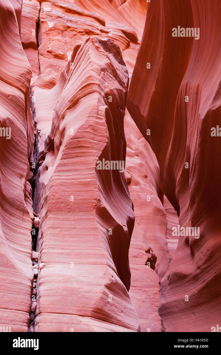 A large crack filled with small rocks separates a eroded sandstone ...