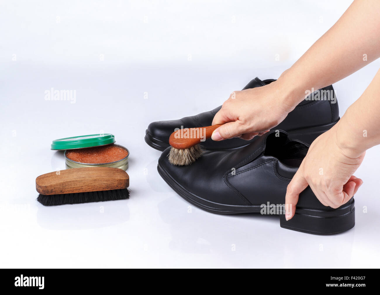 woman's hand polishing black leather shoes with shoe brush on white ...