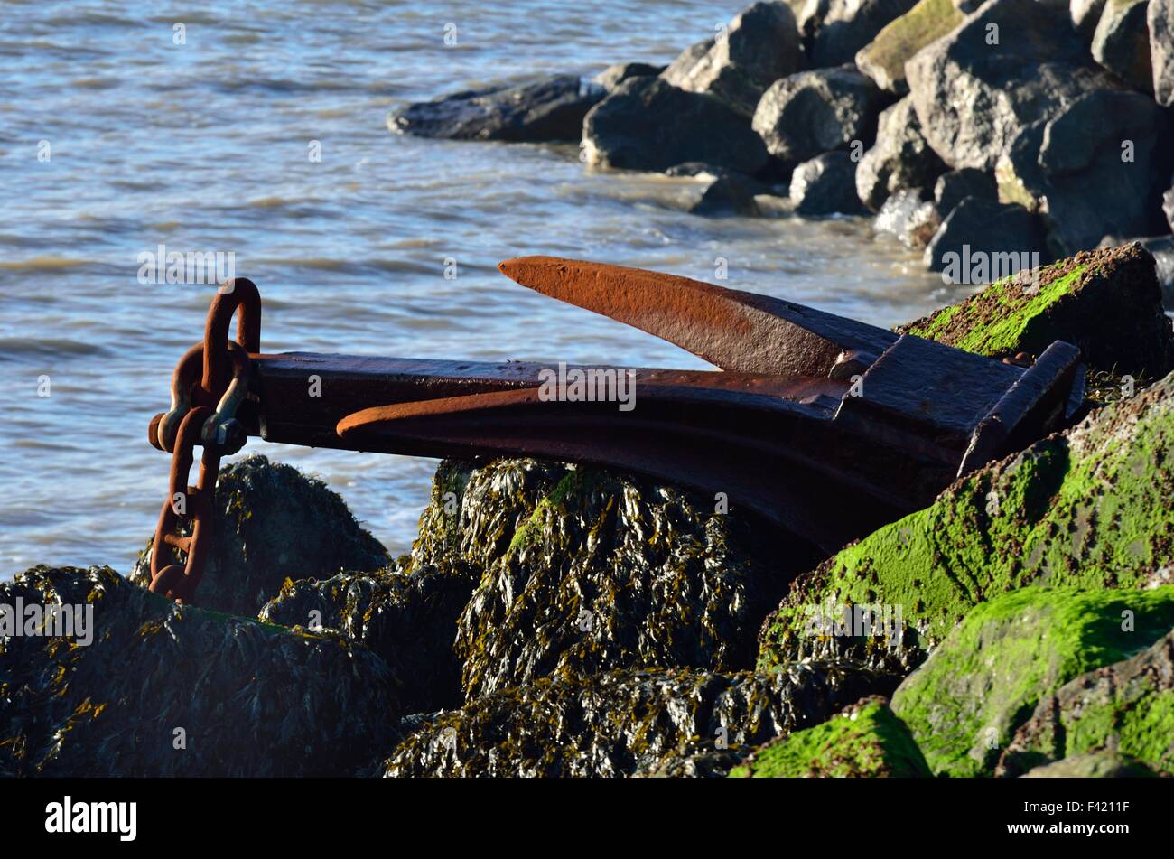 Large iron anchor lying on rocks Stock Photo - Alamy