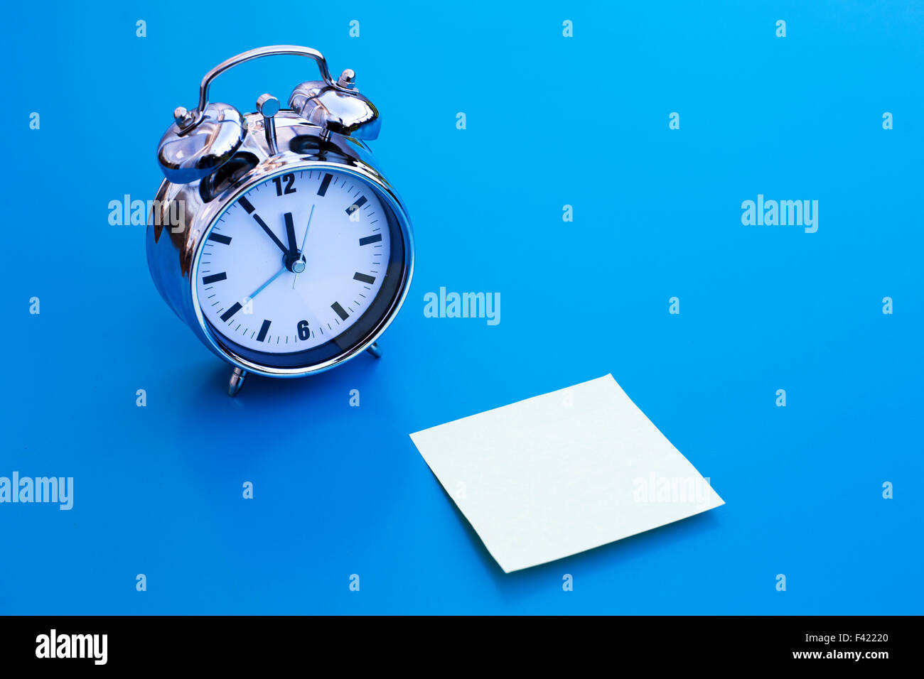 alarm clock with a sticky note on blue table Stock Photo - Alamy
