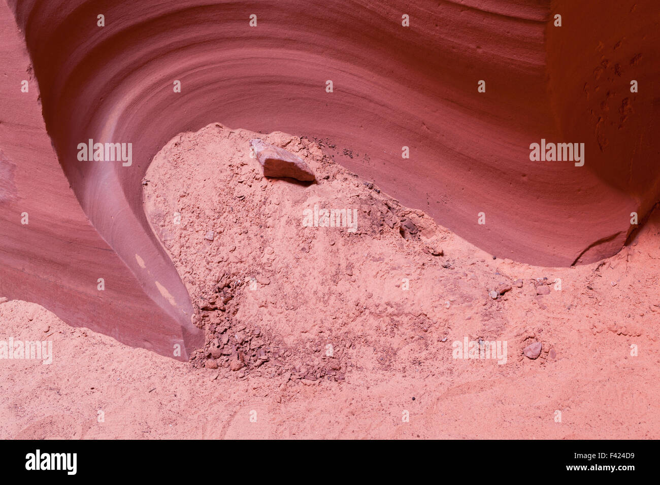 Sand and rock at the base of a sandstone wall that has been carved out ...
