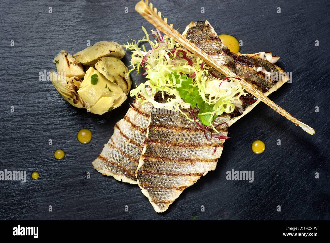 Sea bass fillet dish on black stone plate from top view Stock Photo - Alamy