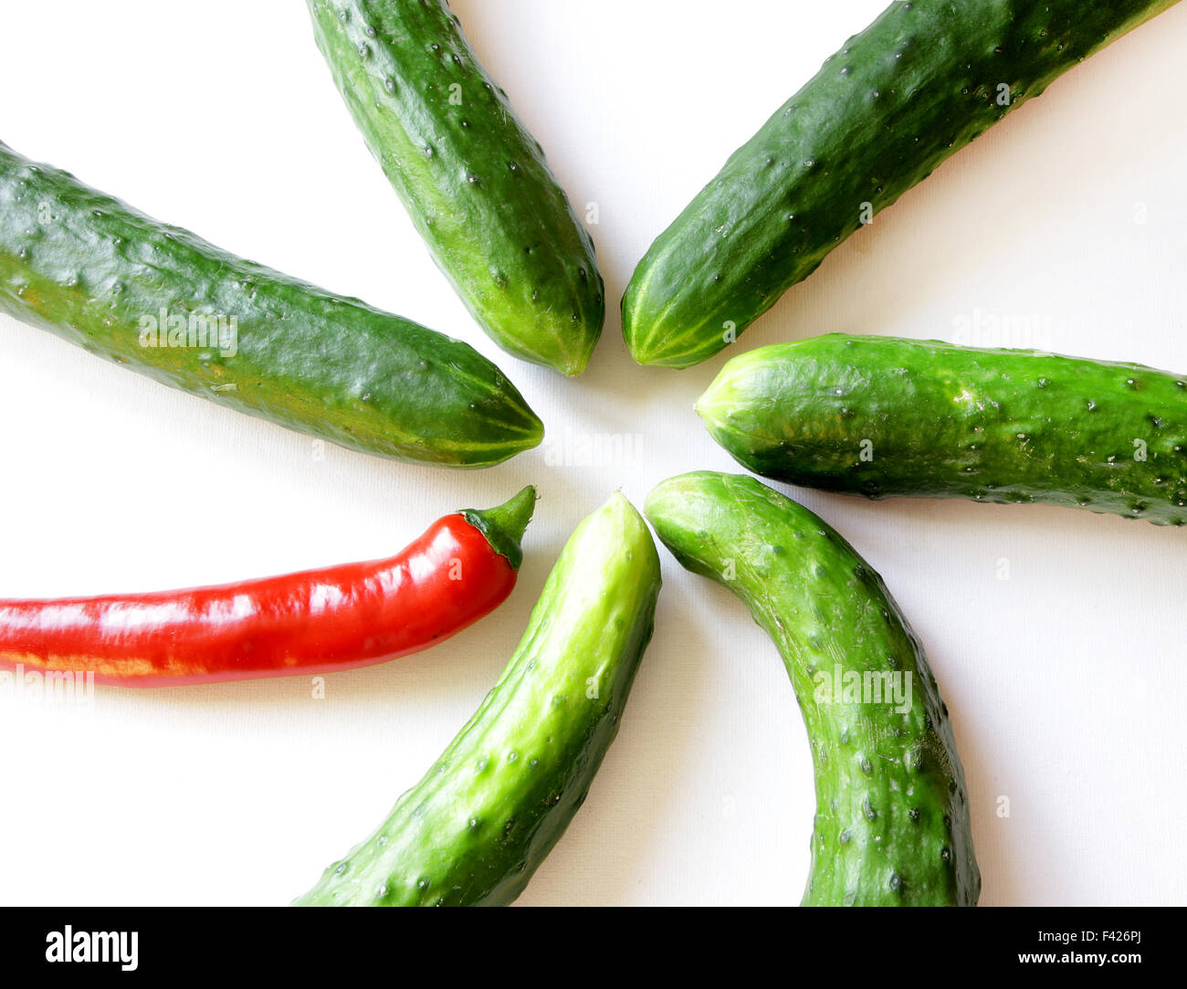 green cucumbers with one red hot chili pepper standing out from the ...
