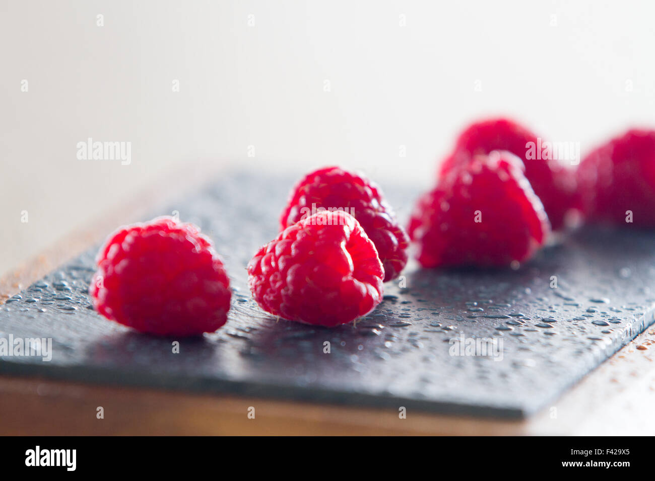 Soft focus of raspberries on kitchen board dark background with water ...