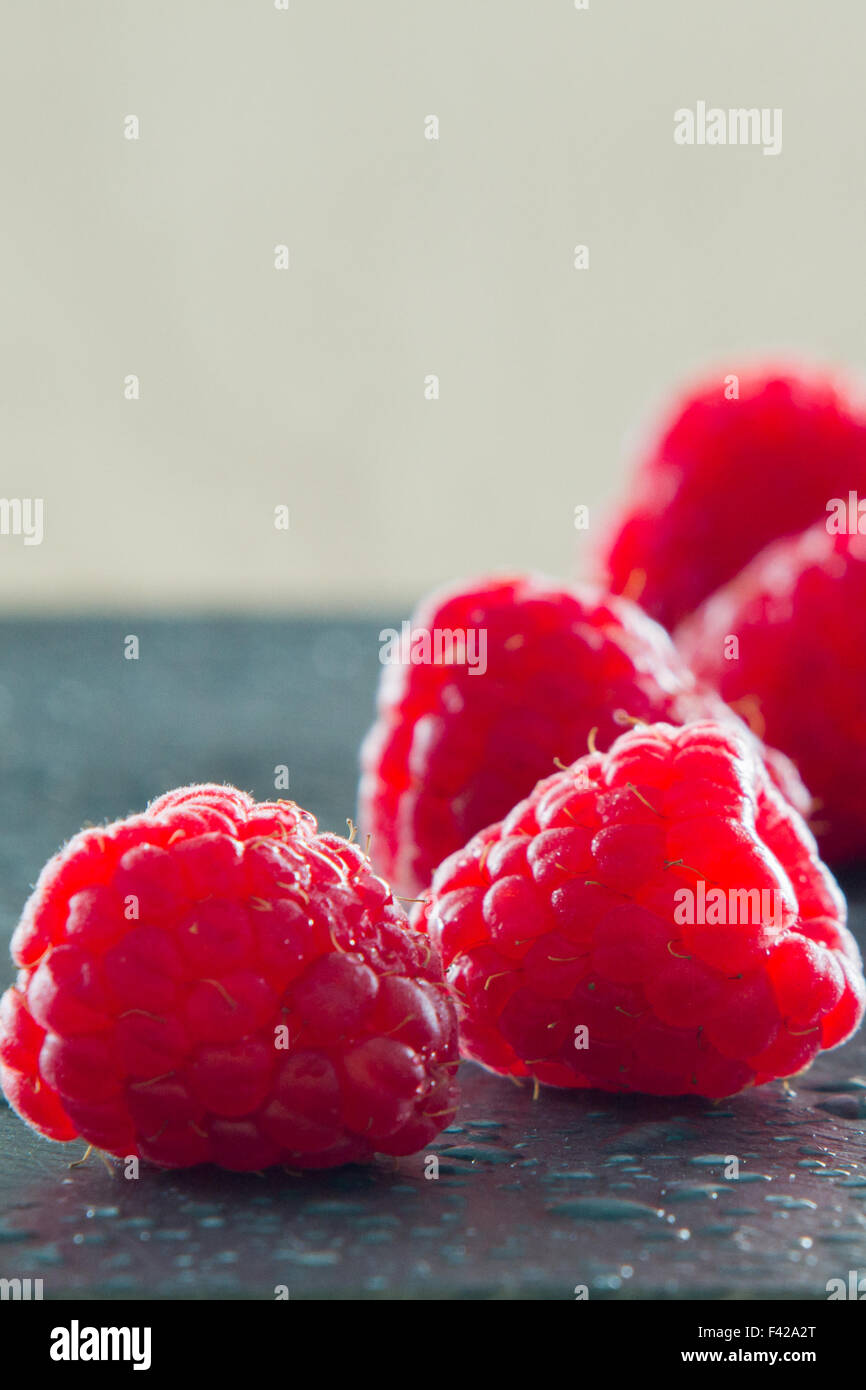 Soft focus of raspberries on kitchen board dark background with water ...