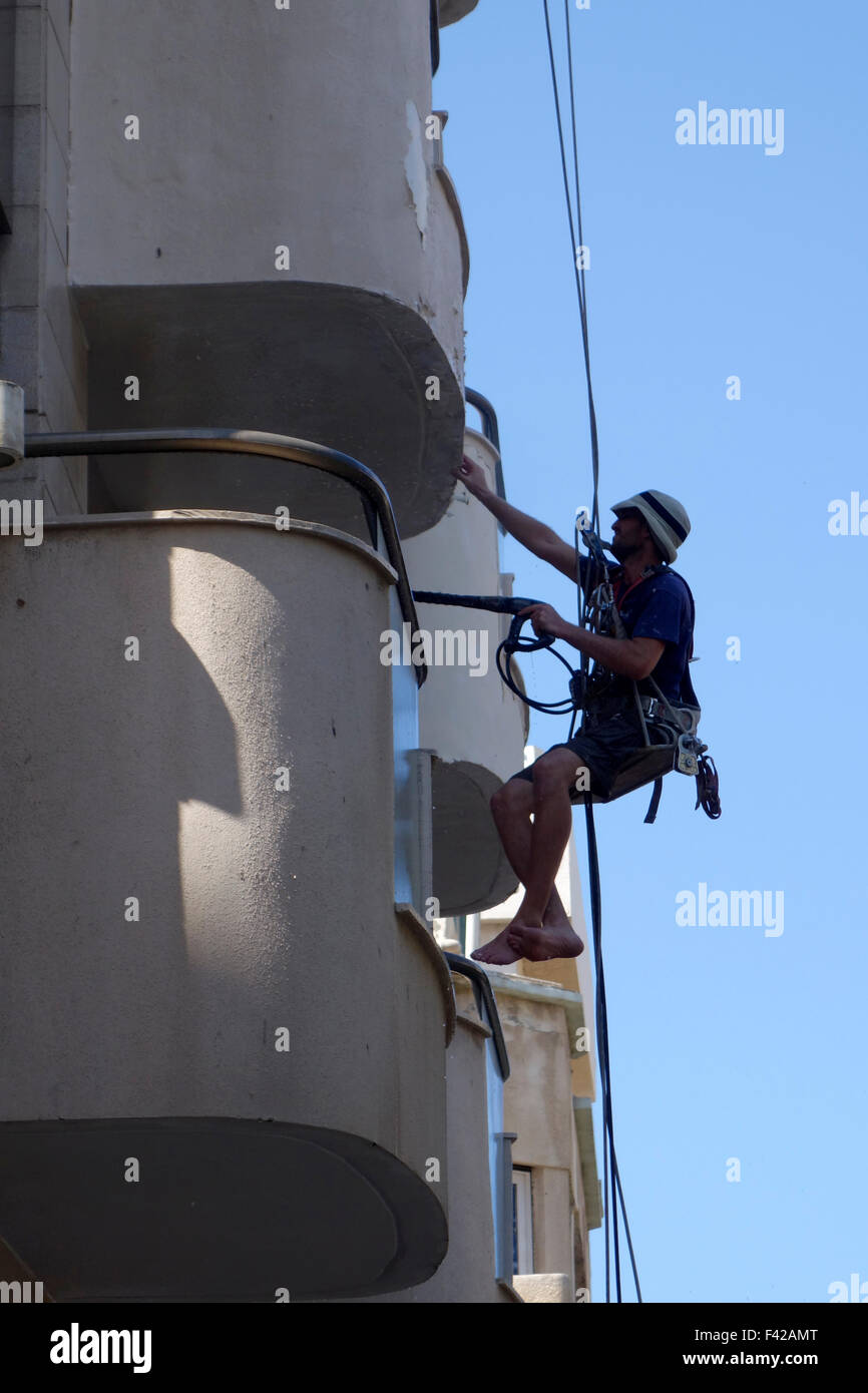 A worker perform maintenance work while abseiling down Stock Photo - Alamy