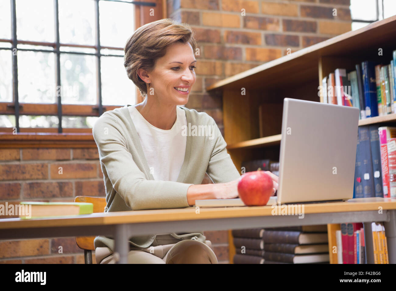 Smiling teacher using laptop at a desk Stock Photo - Alamy