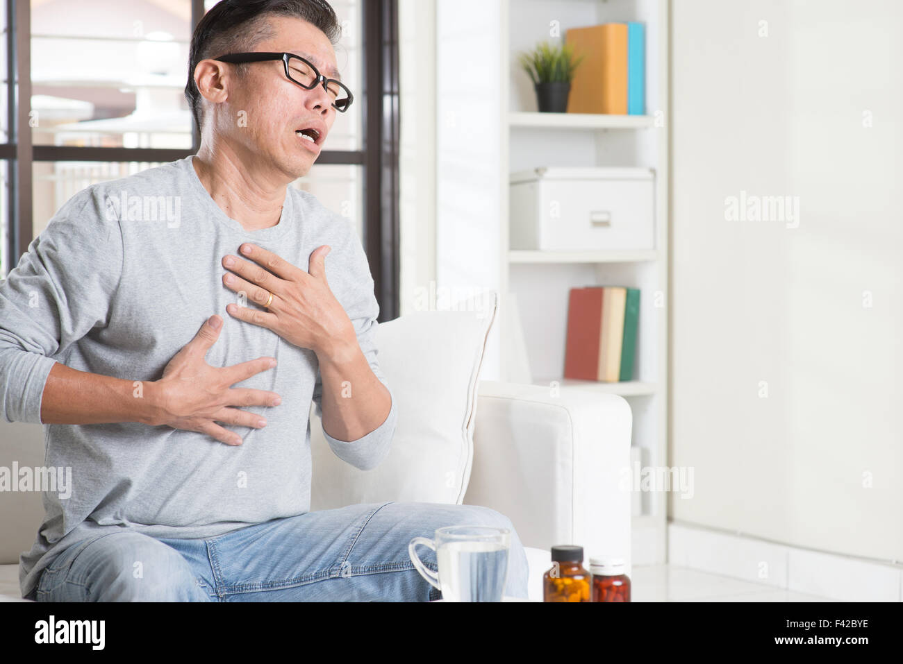 Portrait of casual 50s mature Asian man heartburn, pressing on chest ...