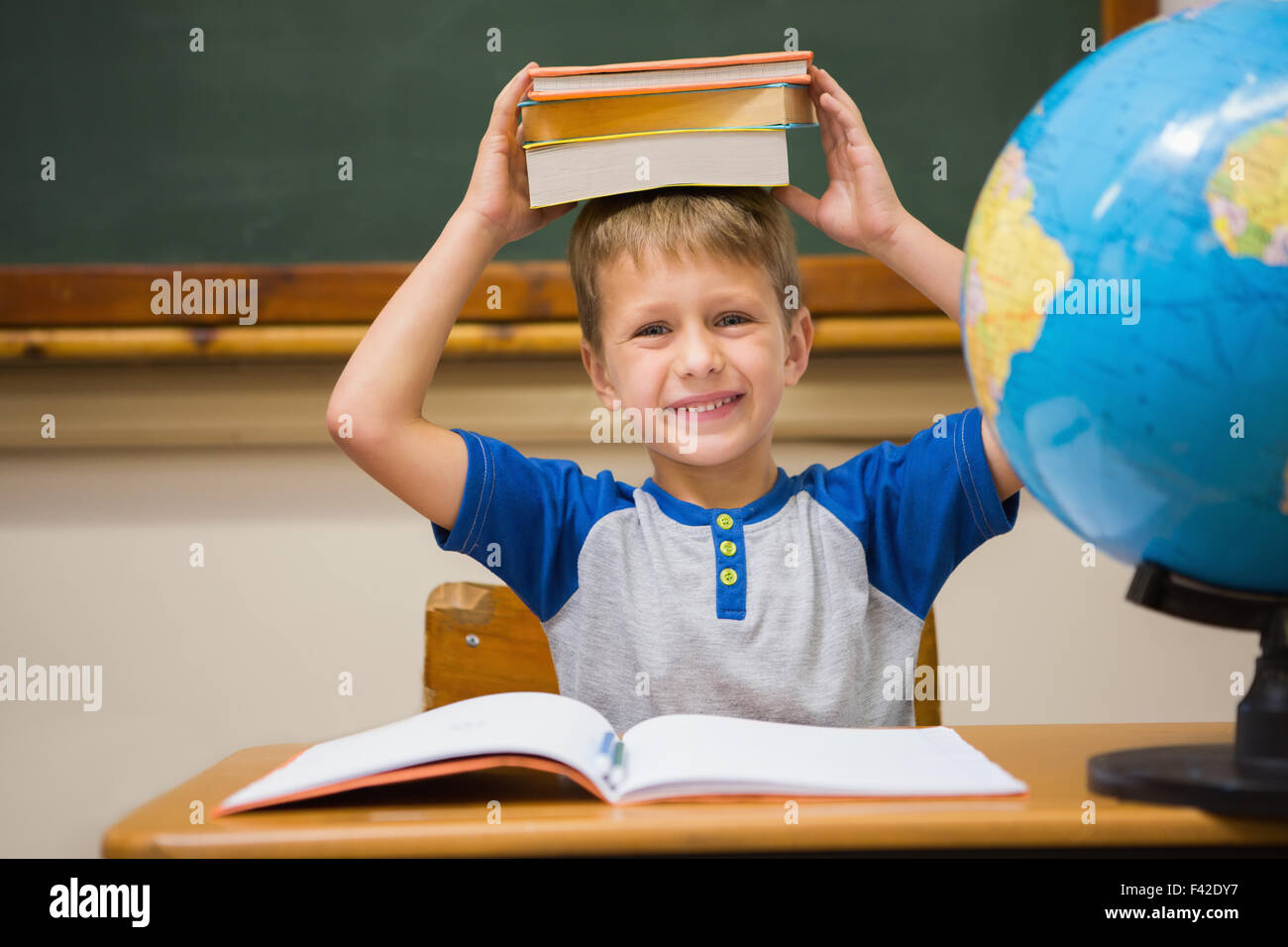 Pupil holding books on his head Stock Photo - Alamy