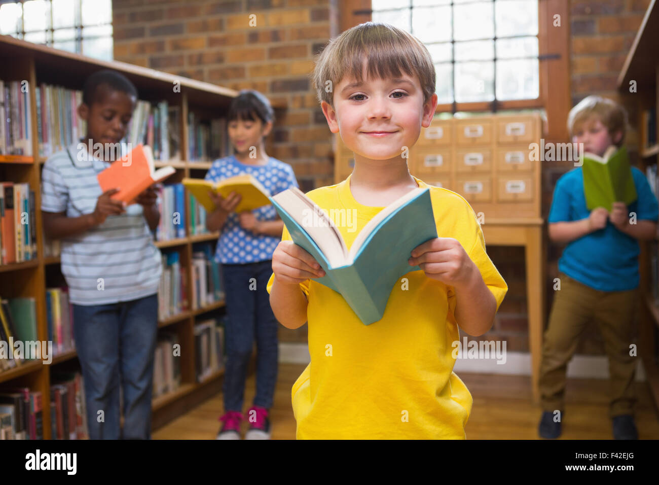 Cute pupils reading books at library Stock Photo - Alamy