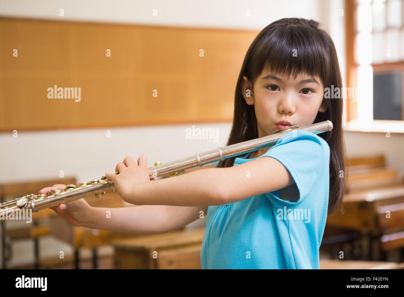 Cute pupil playing flute in classroom Stock Photo - Alamy