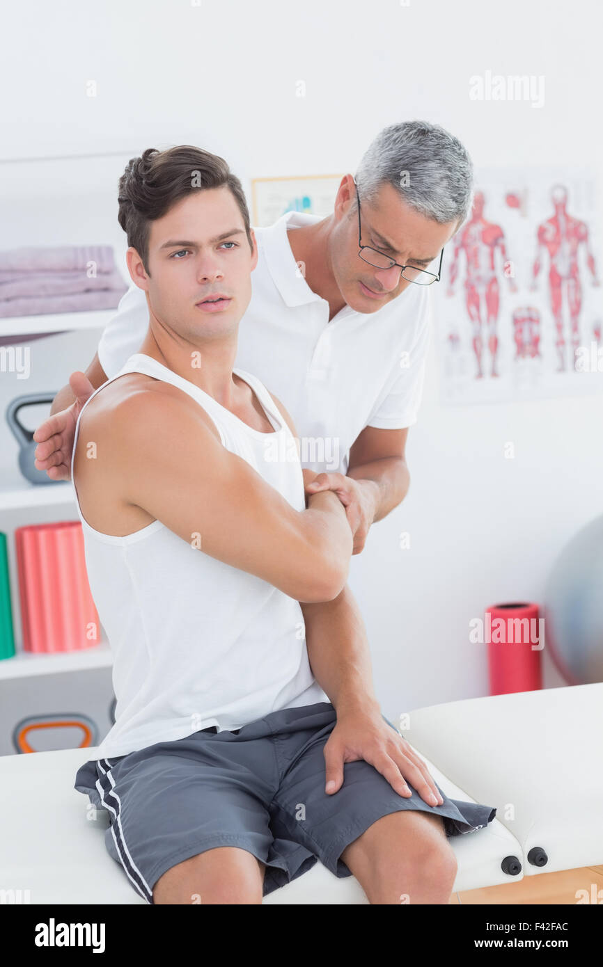 Doctor stretching a young man arm Stock Photo - Alamy